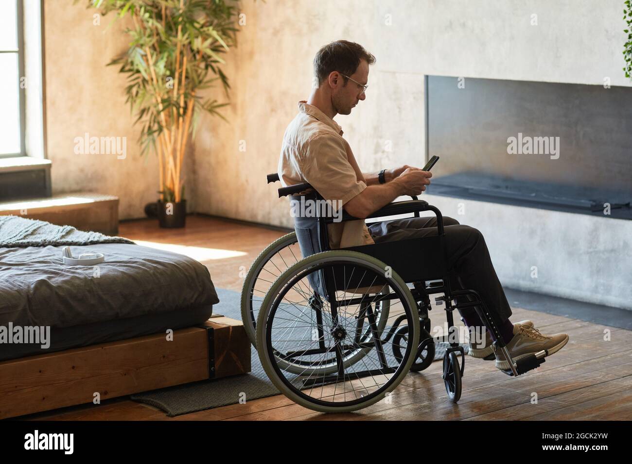 Side view full length portrait of modern adult man in wheelchair using ...