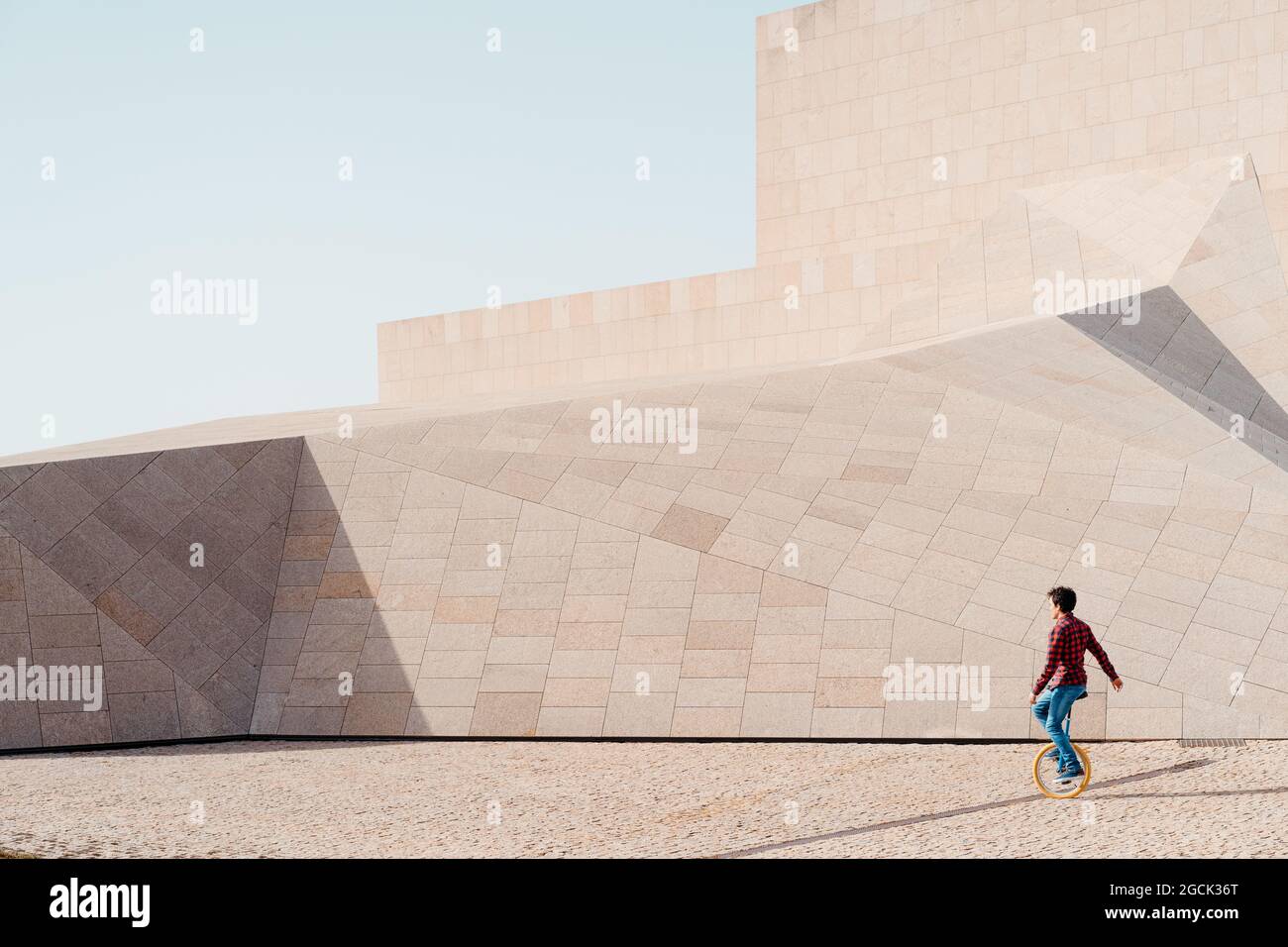Side view of unrecognizable male riding unicycle against contemporary ...