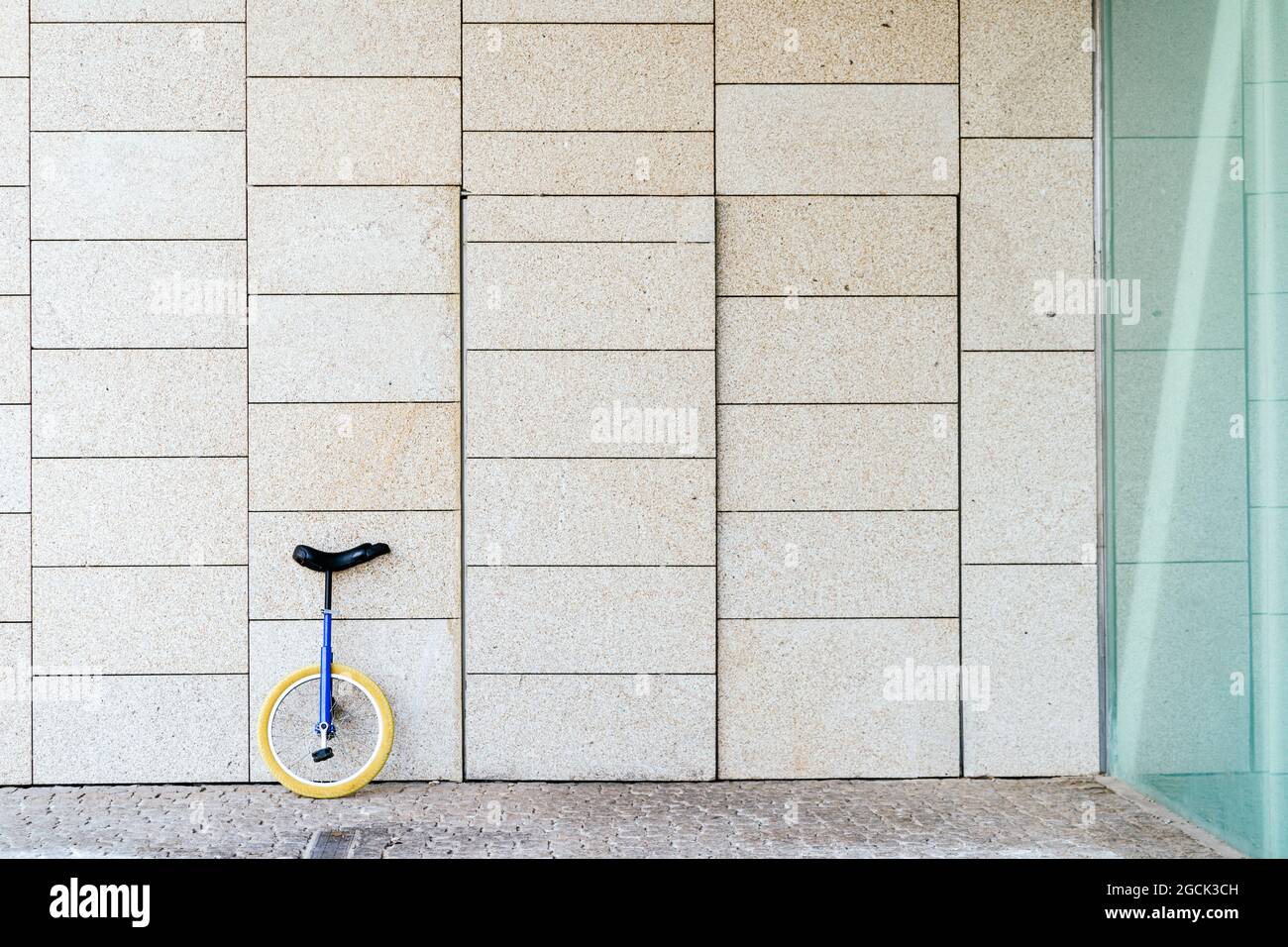 Modern unicycle parked near stone wall of contemporary building with ...