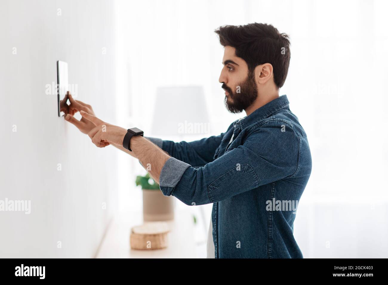 Automation domestic system. Arab man using digital tablet on wall with ...