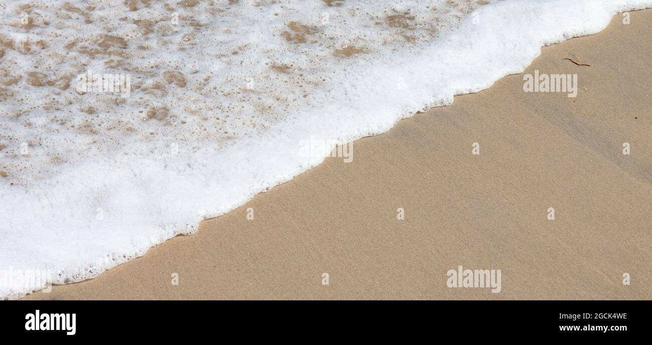 Wave of Atlantic Ocean, salt water and beach sand split diagonally ...