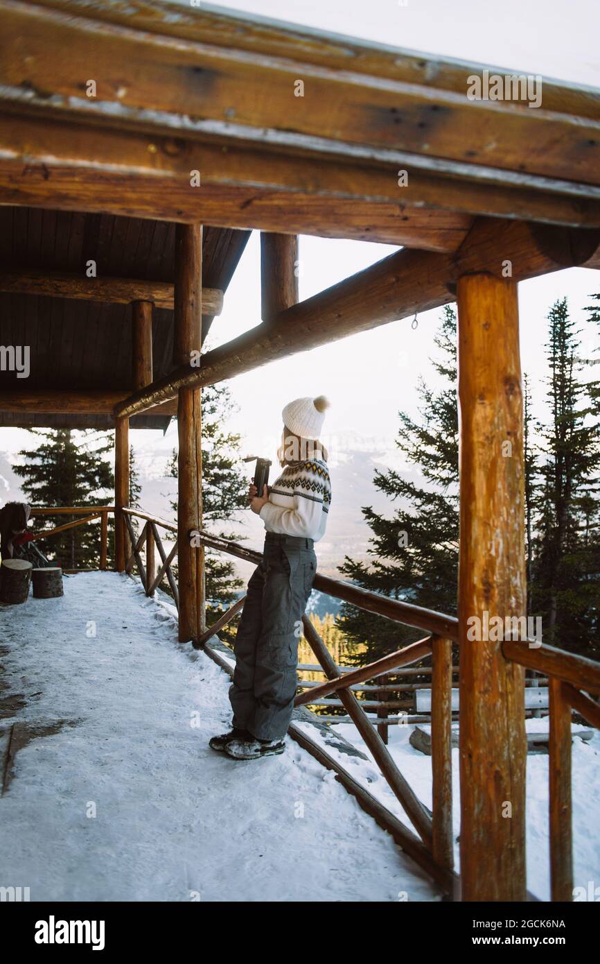 Female traveler enjoying hot drink from thermos while resting in wooden ...