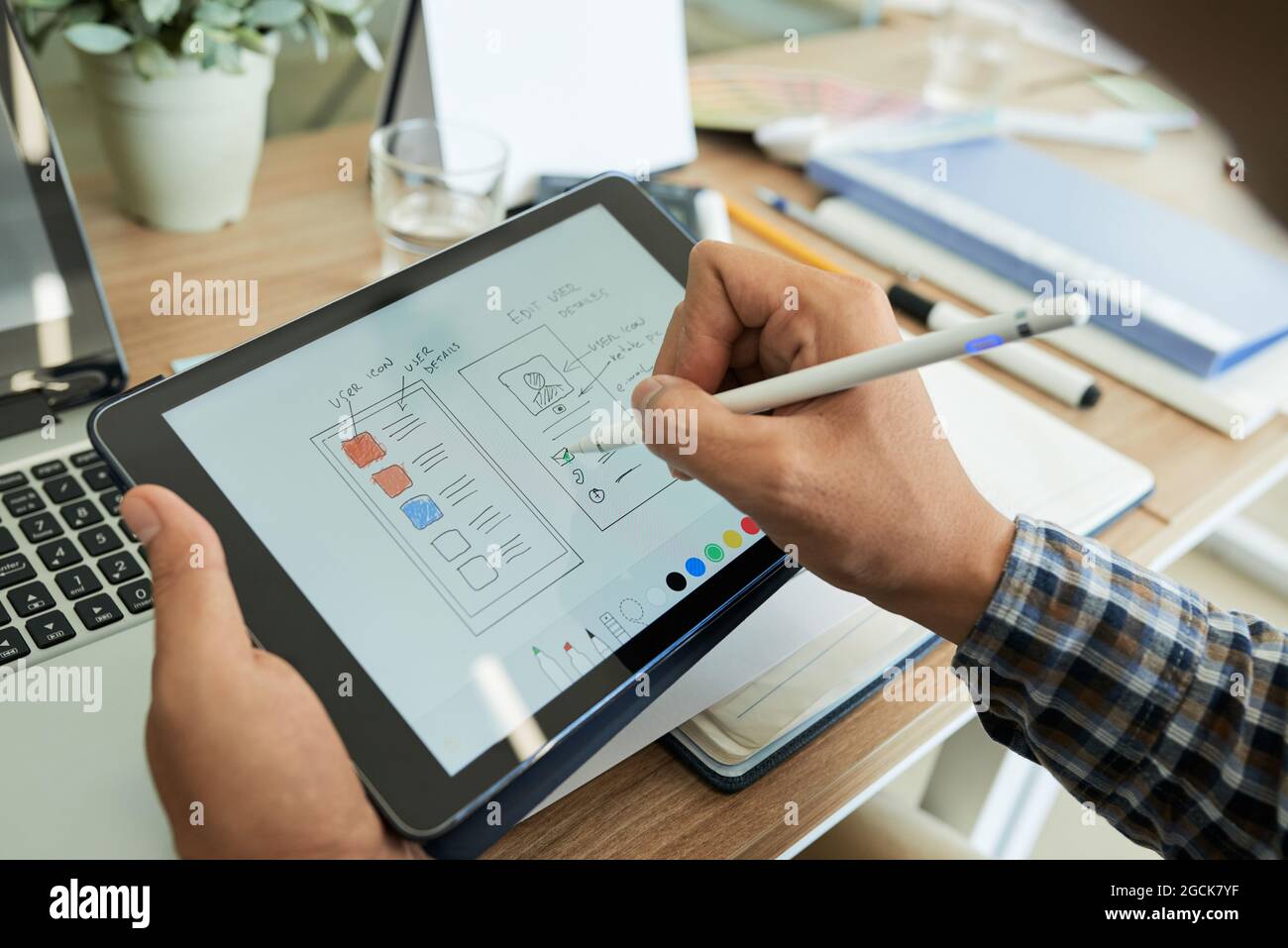 Hands of UI designer drawing sketch of mobile application on tablet ...