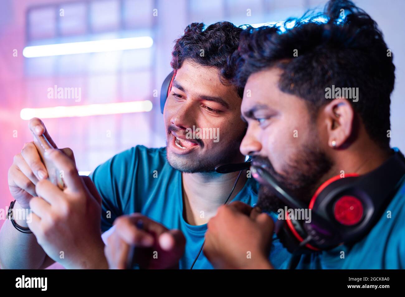 Two gamers discussing about game play by looking into mobile phone at ...