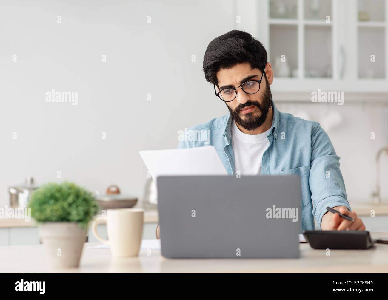 Stressed arab man calculating home budget, sitting in kitchen, young ...