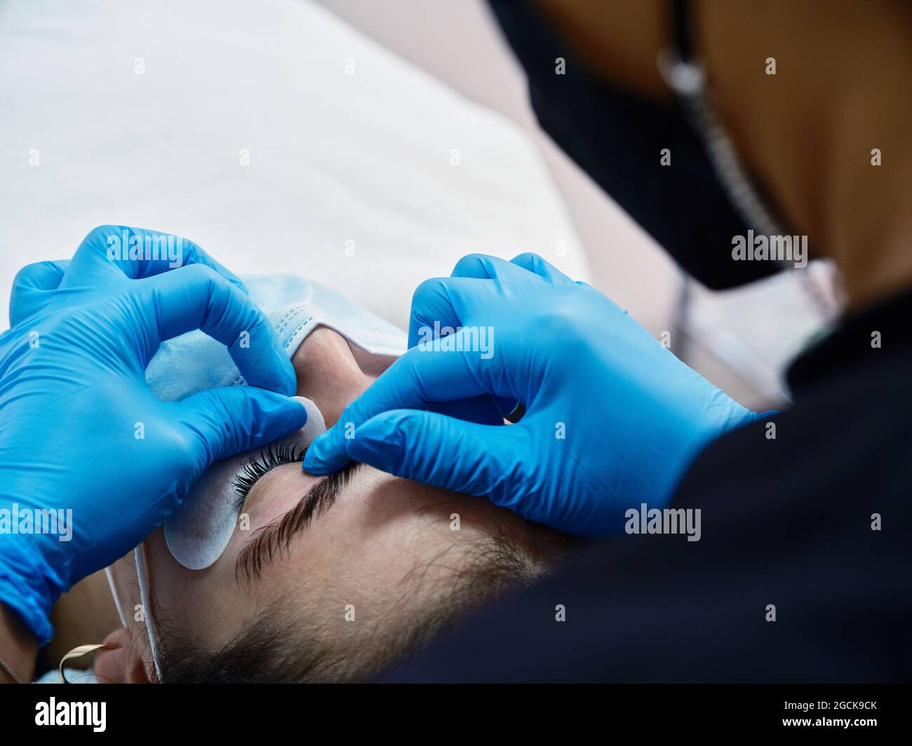 Crop anonymous beauty master applying lash lift shield on eyelid of ...