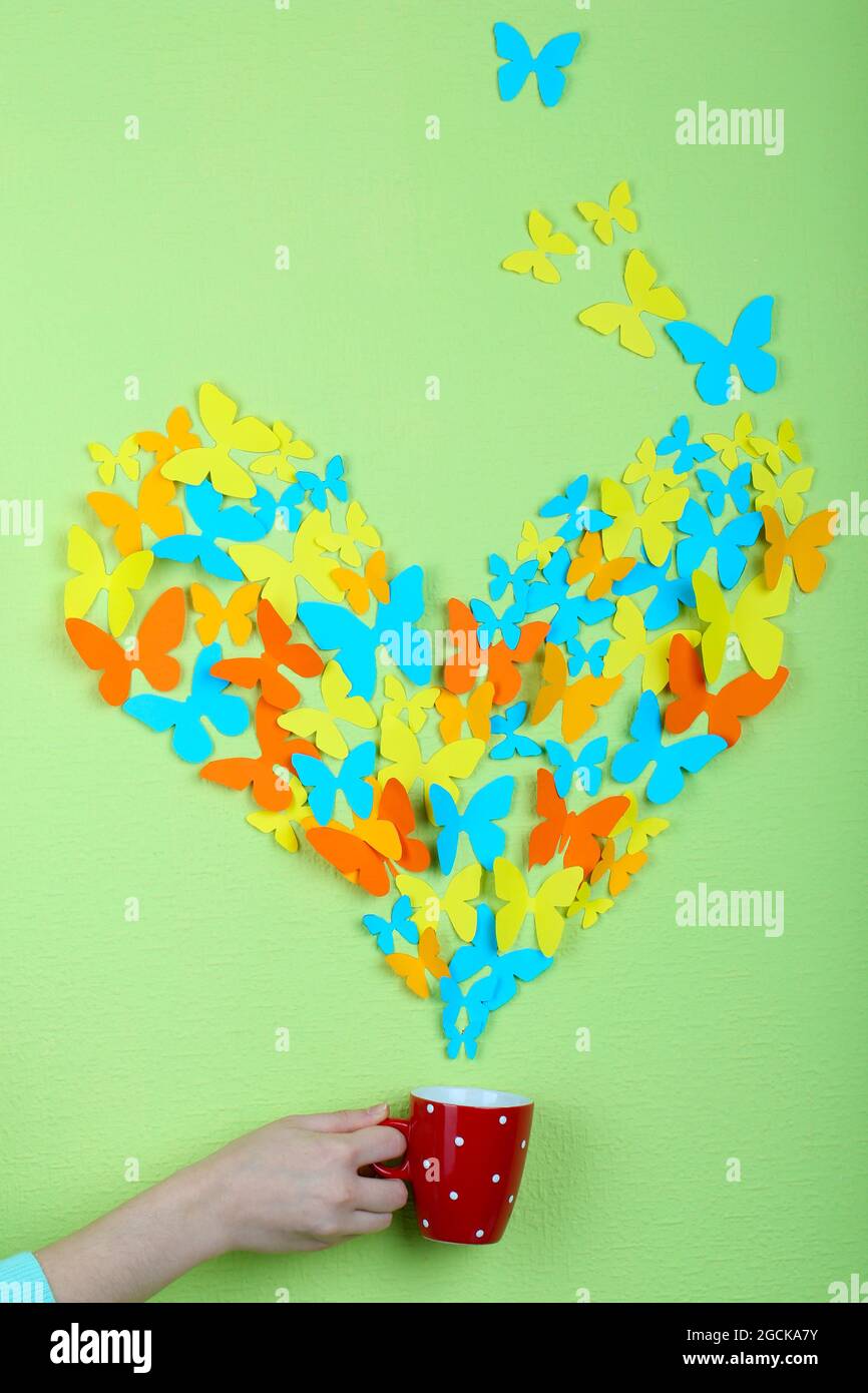 Paper butterflies fly out of cup on green wall background Stock Photo ...