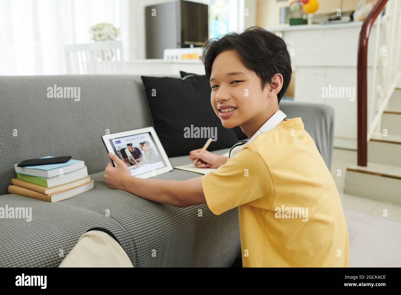 Portrait of smiling teenage boy using app on tablet computer when ...