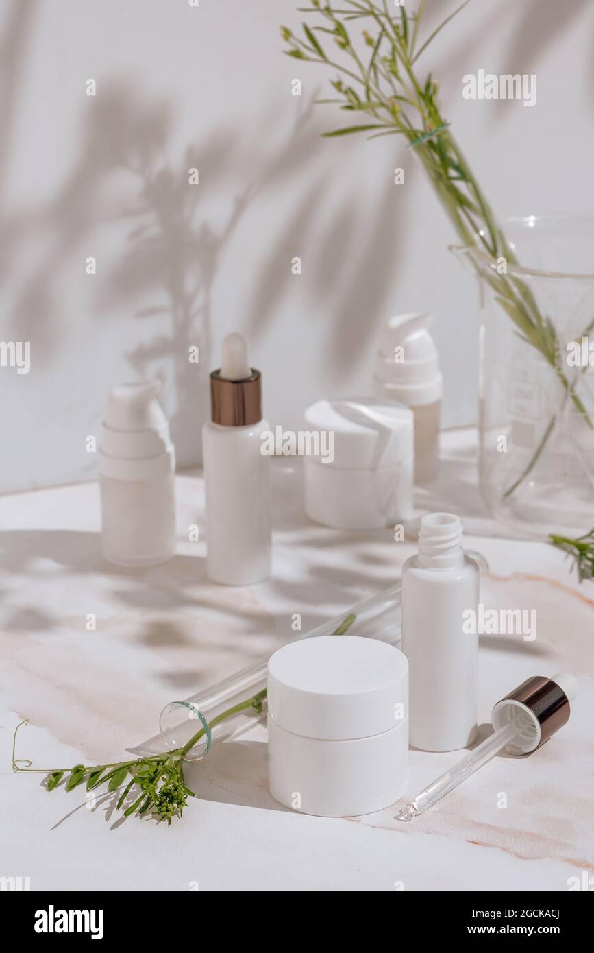 Natural cosmetic products in white packaging with laboratory glassware ...