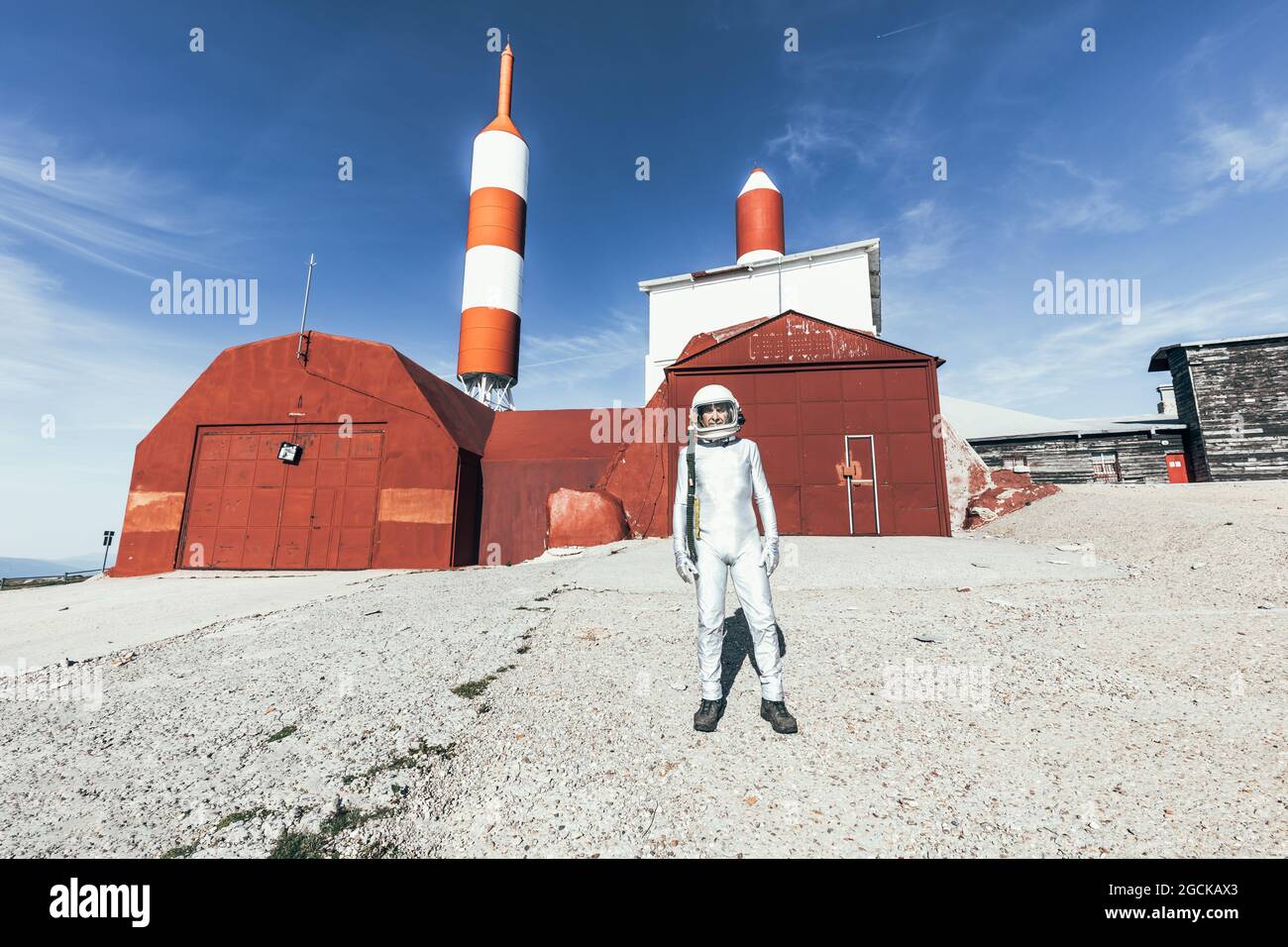 Full body man in spacesuit standing on rocky ground against striped ...