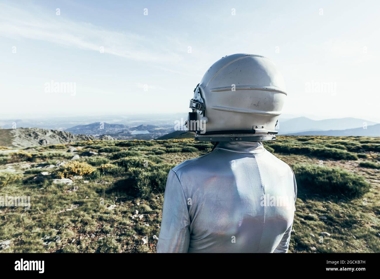 Back view male astronaut in spacesuit and helmet standing on grass and ...