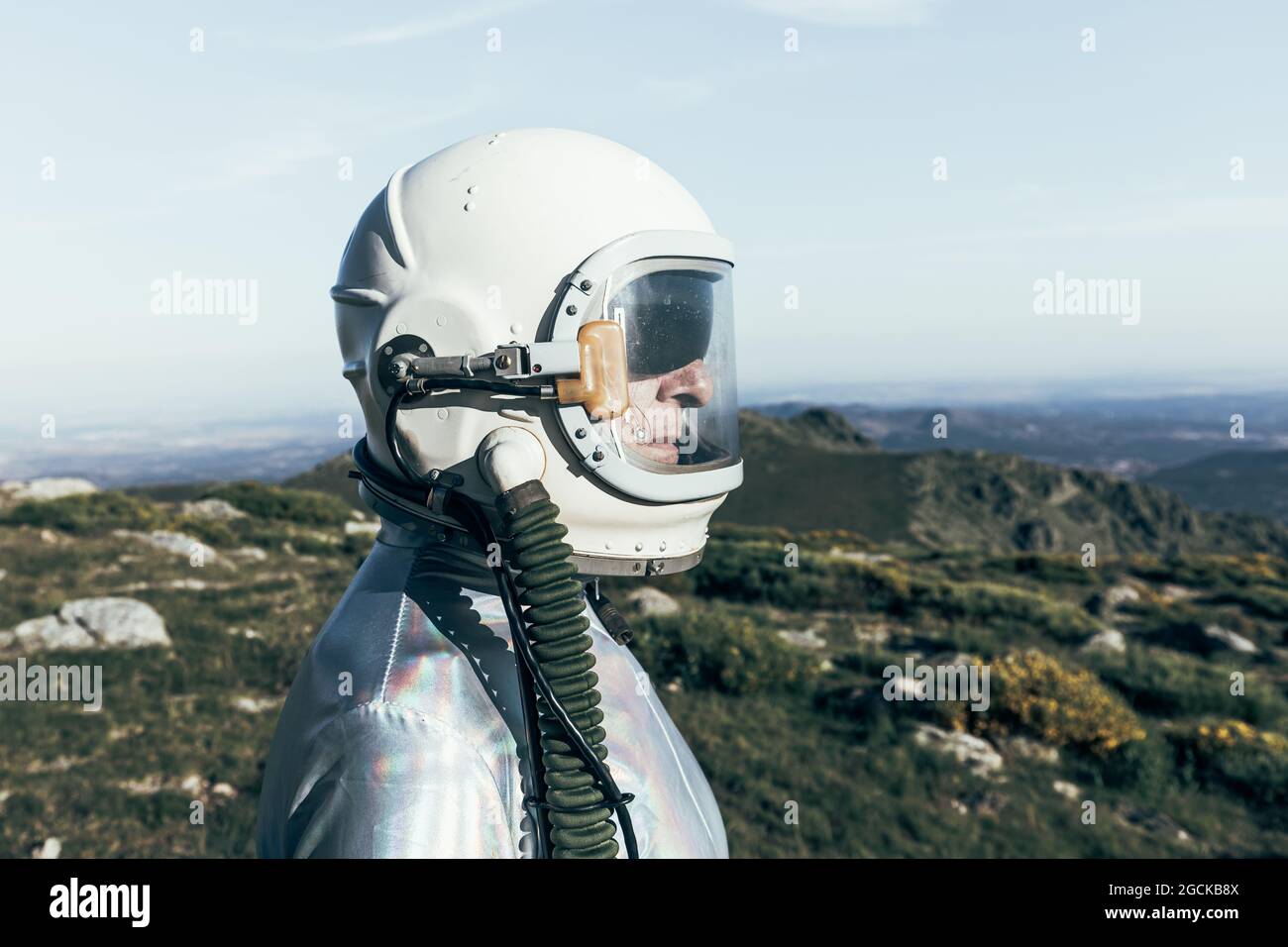 Side view male astronaut in spacesuit and helmet standing on grass and ...