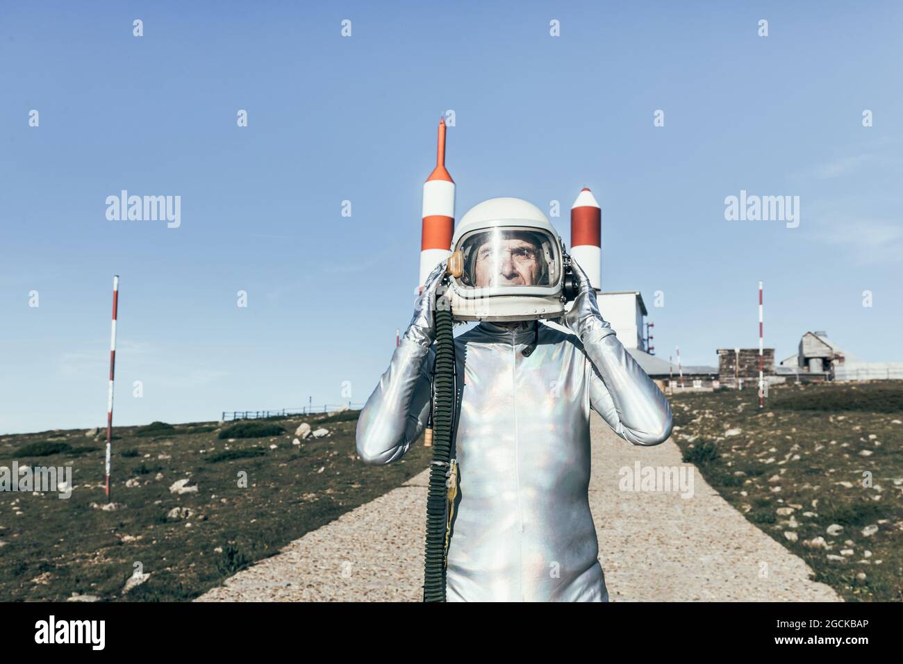 Senior man in spacesuit taking off protective helmet while standing on ...
