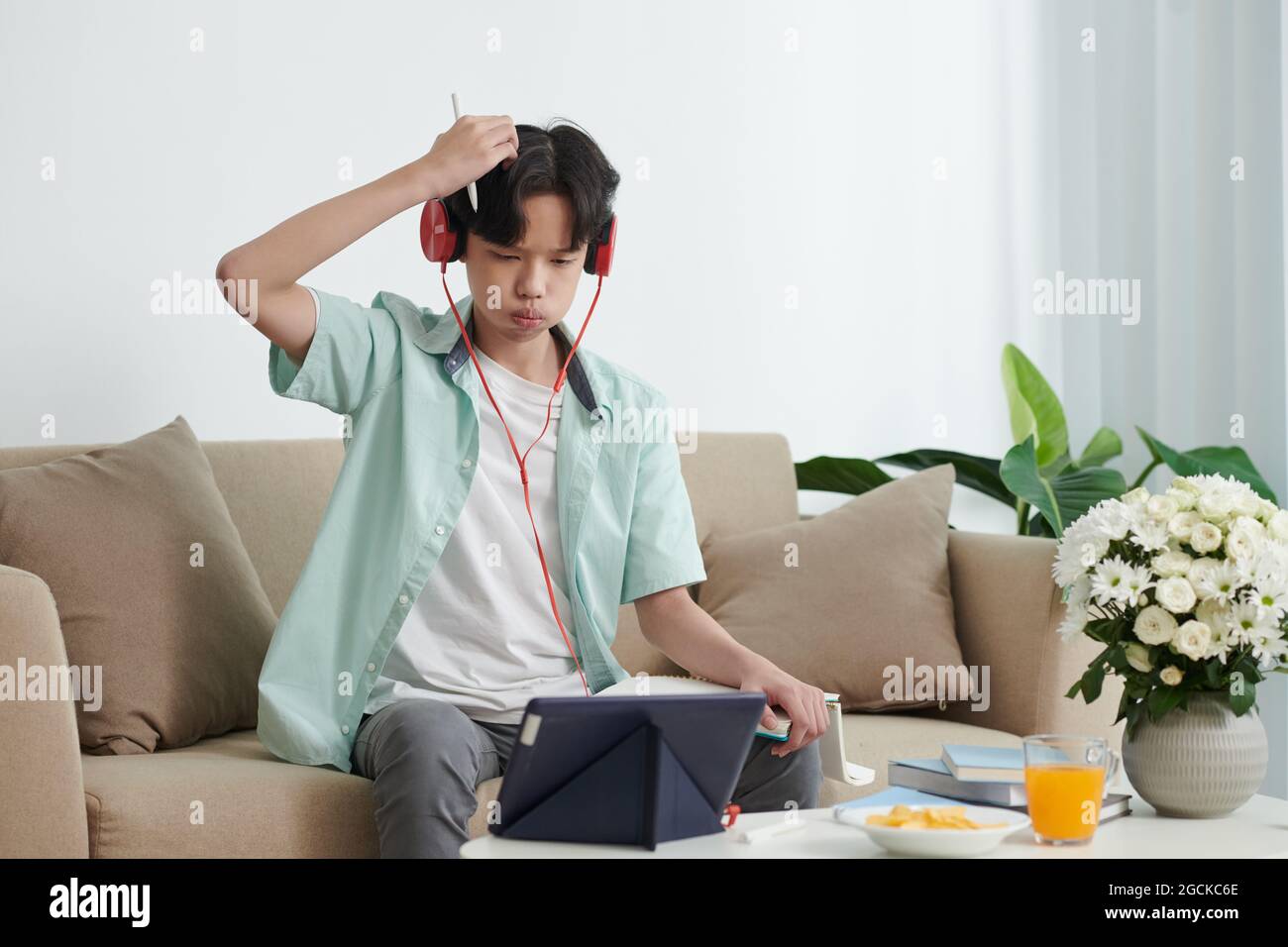 Confused teenage boy in headphonea scratching head when watching ...