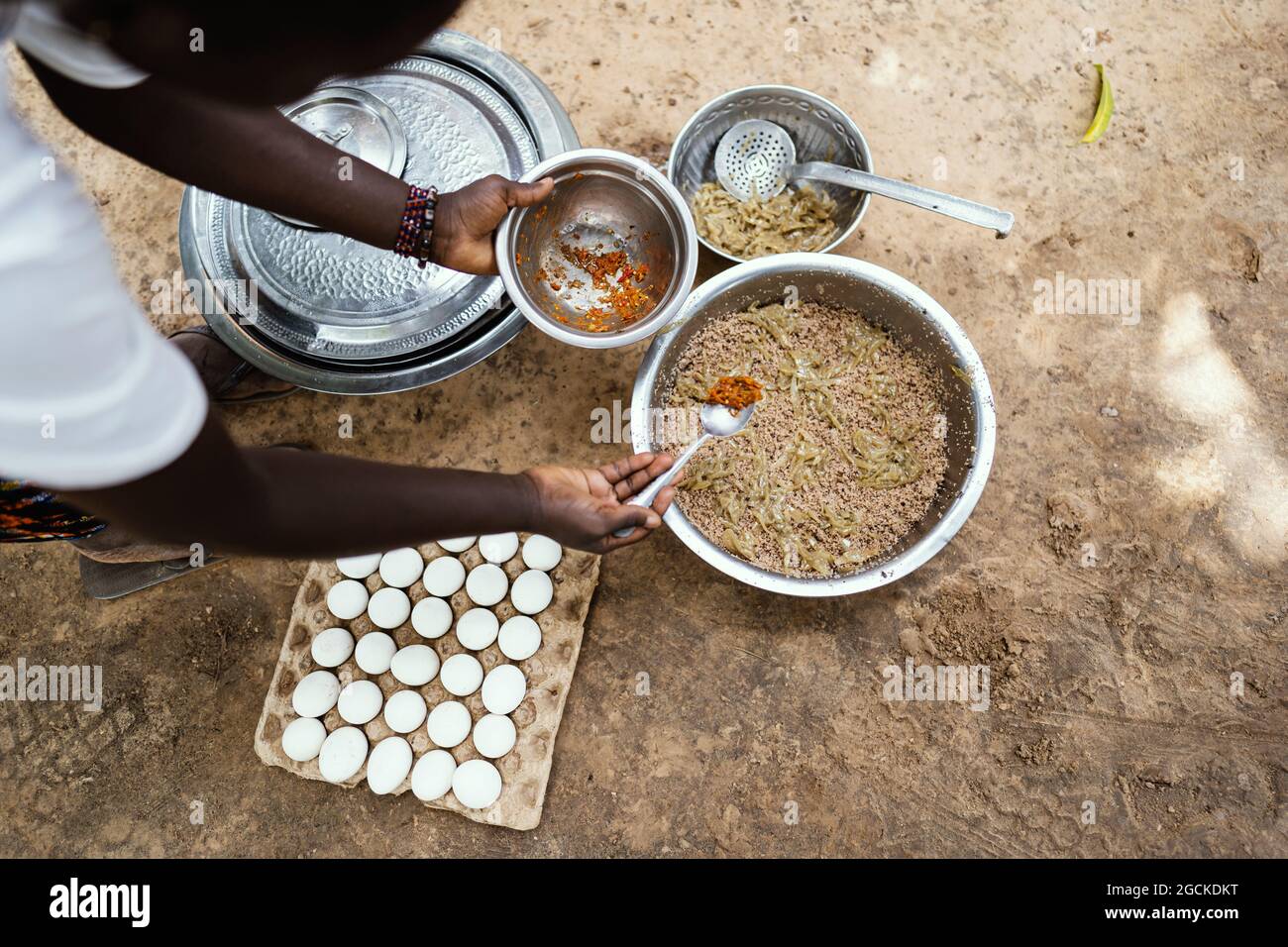 In this image, a black African cook adds spice to a simple dish she's ...