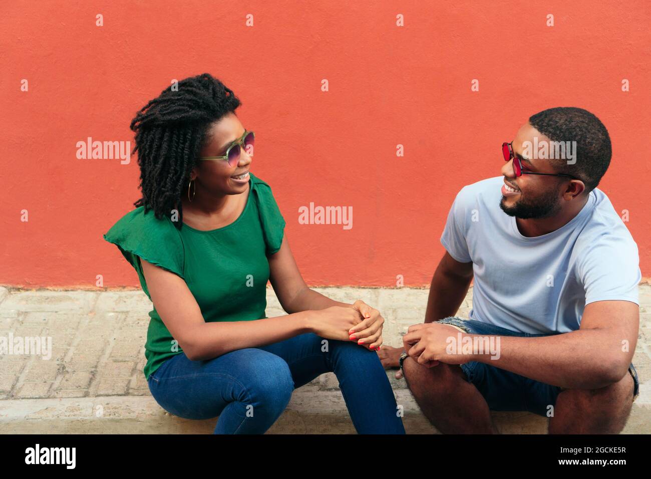 Black couple sitting on the street and looking to the side Stock Photo ...
