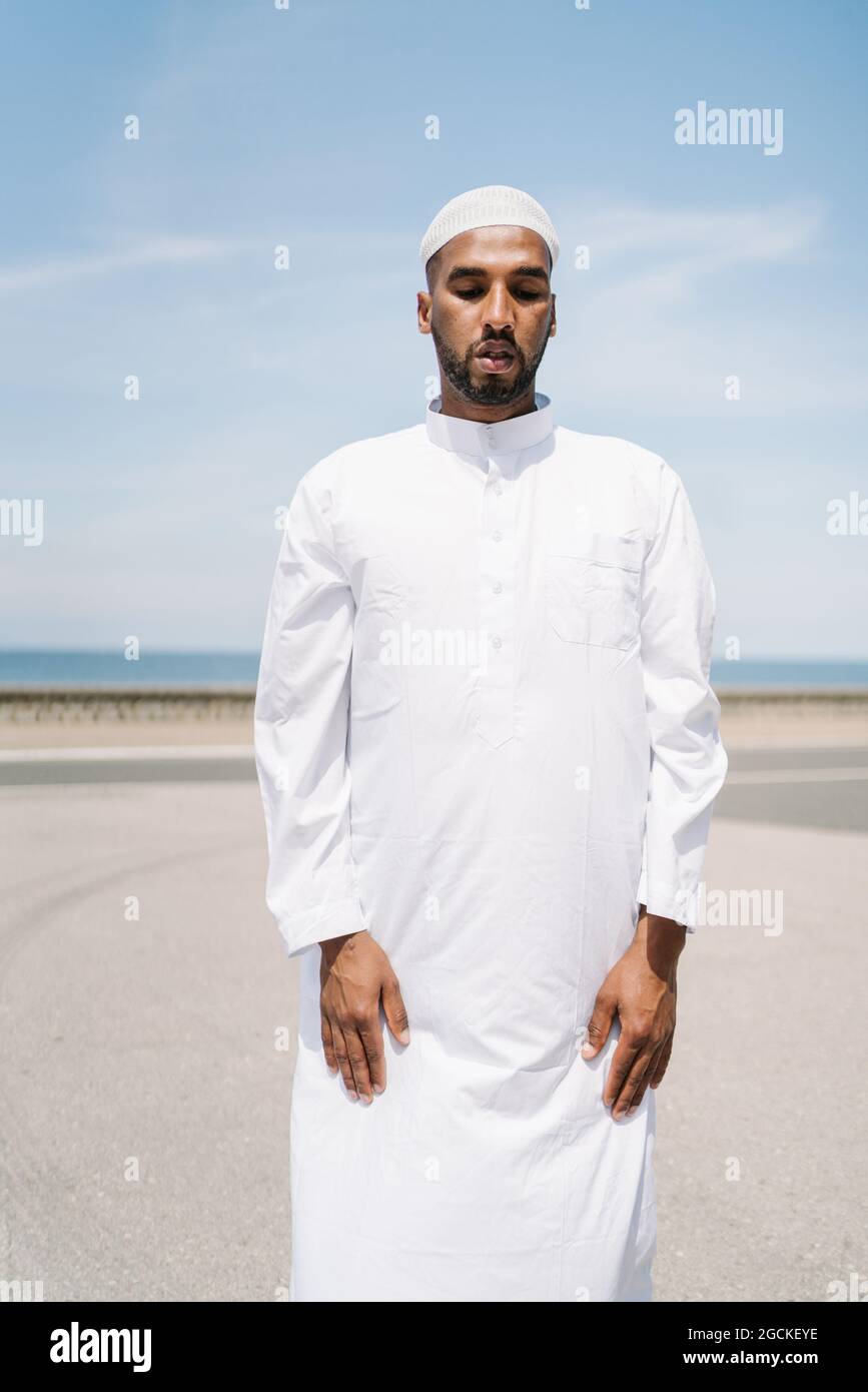 Full boy Islamic male in traditional white clothes standing on rug and ...