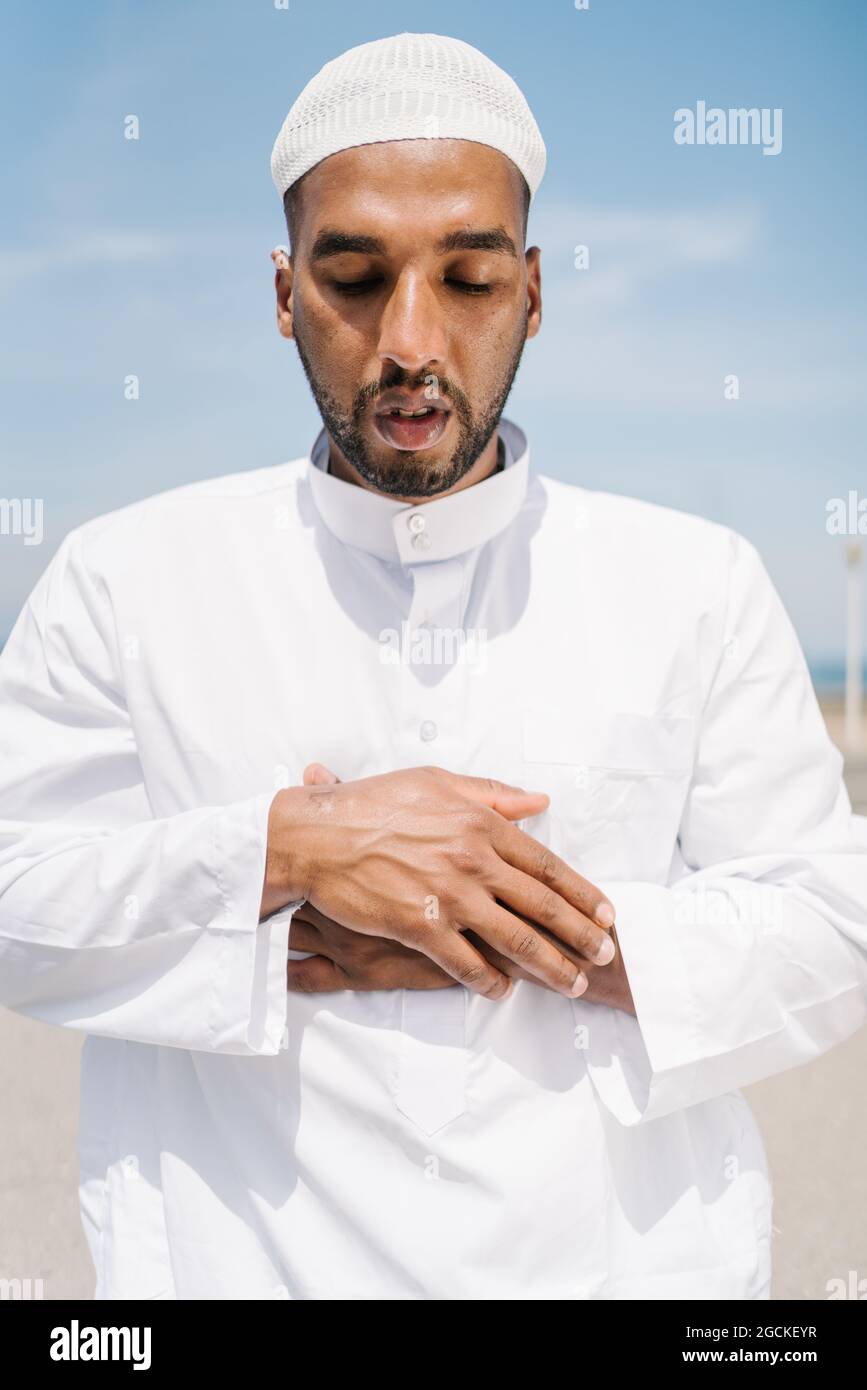 Full boy Islamic male in traditional white clothes standing on rug and ...