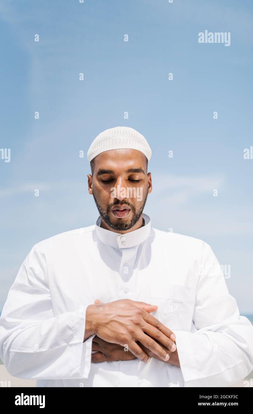 Full boy Islamic male in traditional white clothes standing on rug and ...