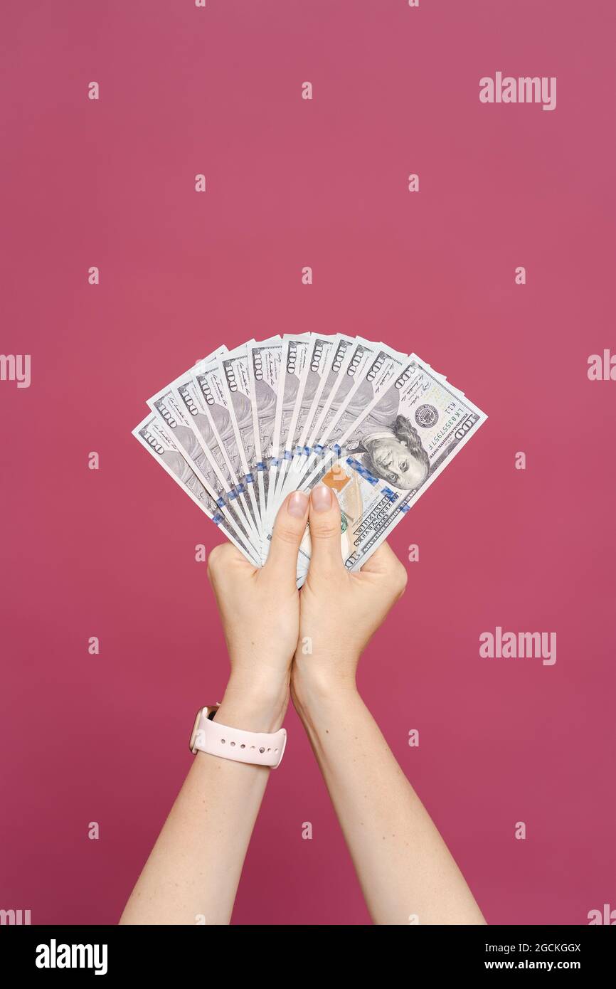 Woman hand with stack of dollars isolated on pink background with copy ...