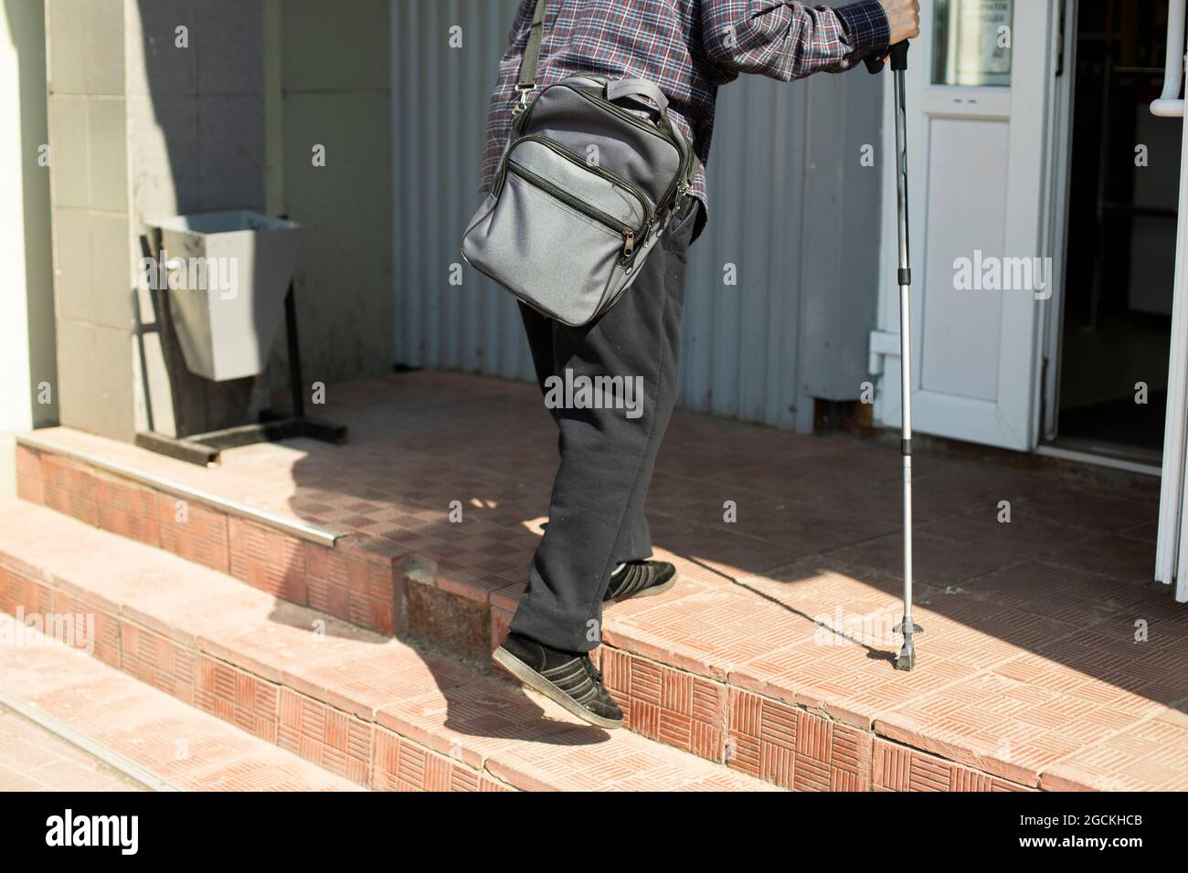 A man with a support stick. The old man climbs the steps. A man enters ...