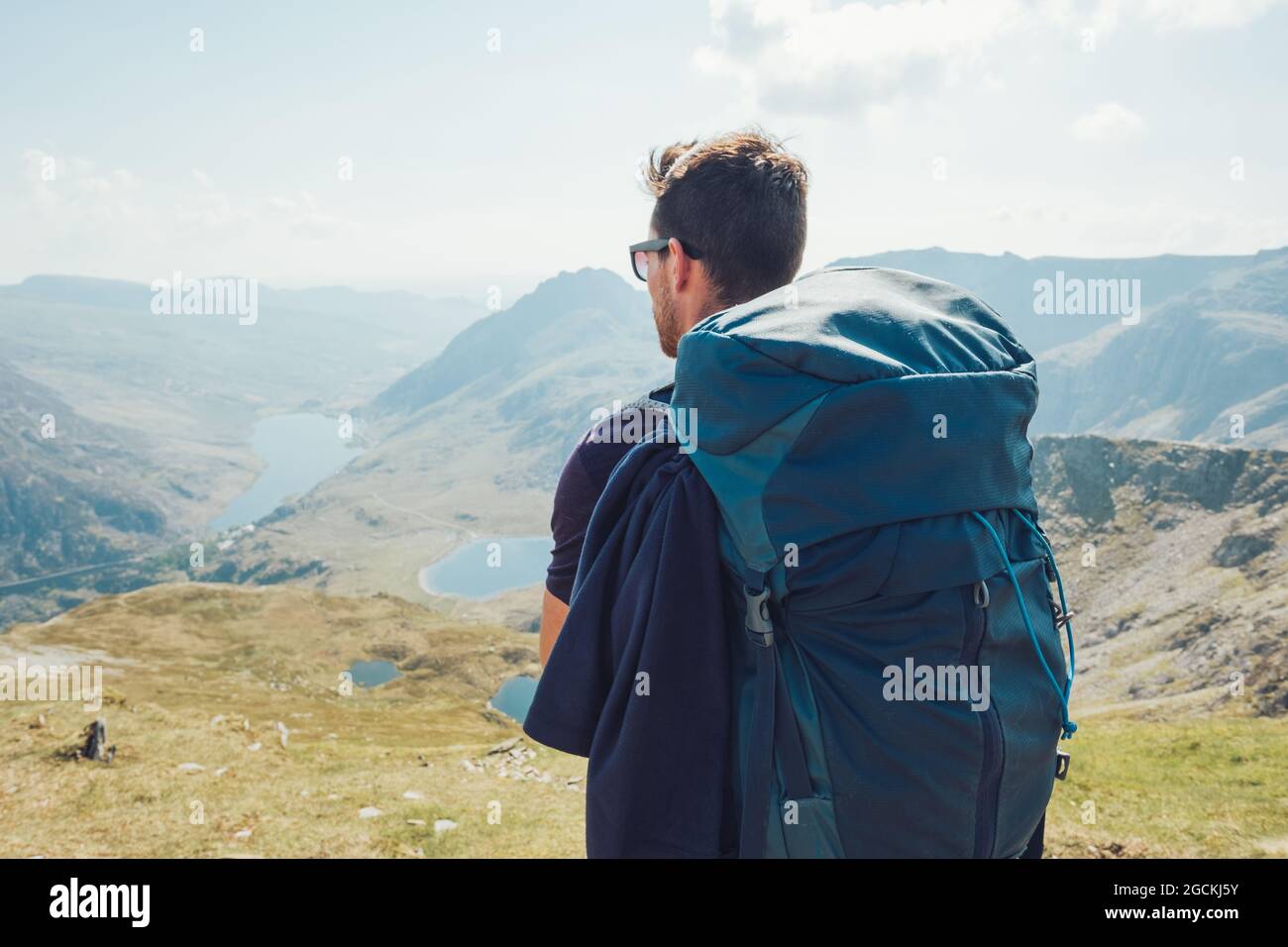 Back view of male hiker with backpack enjoying scenery of highlands ...
