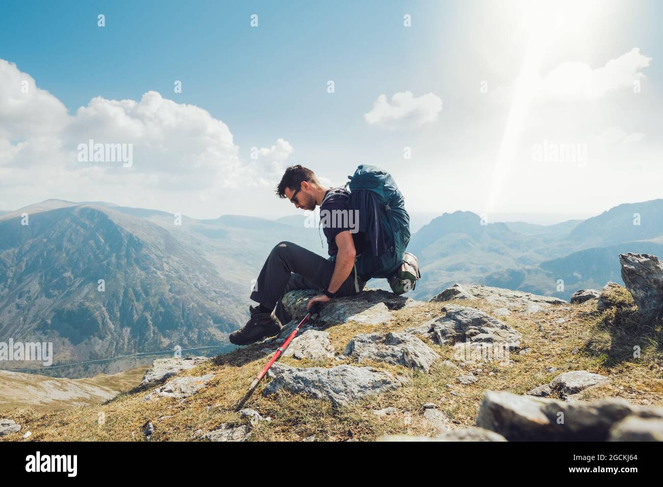 Side view of traveling man sitting resting during hiking in mountains ...