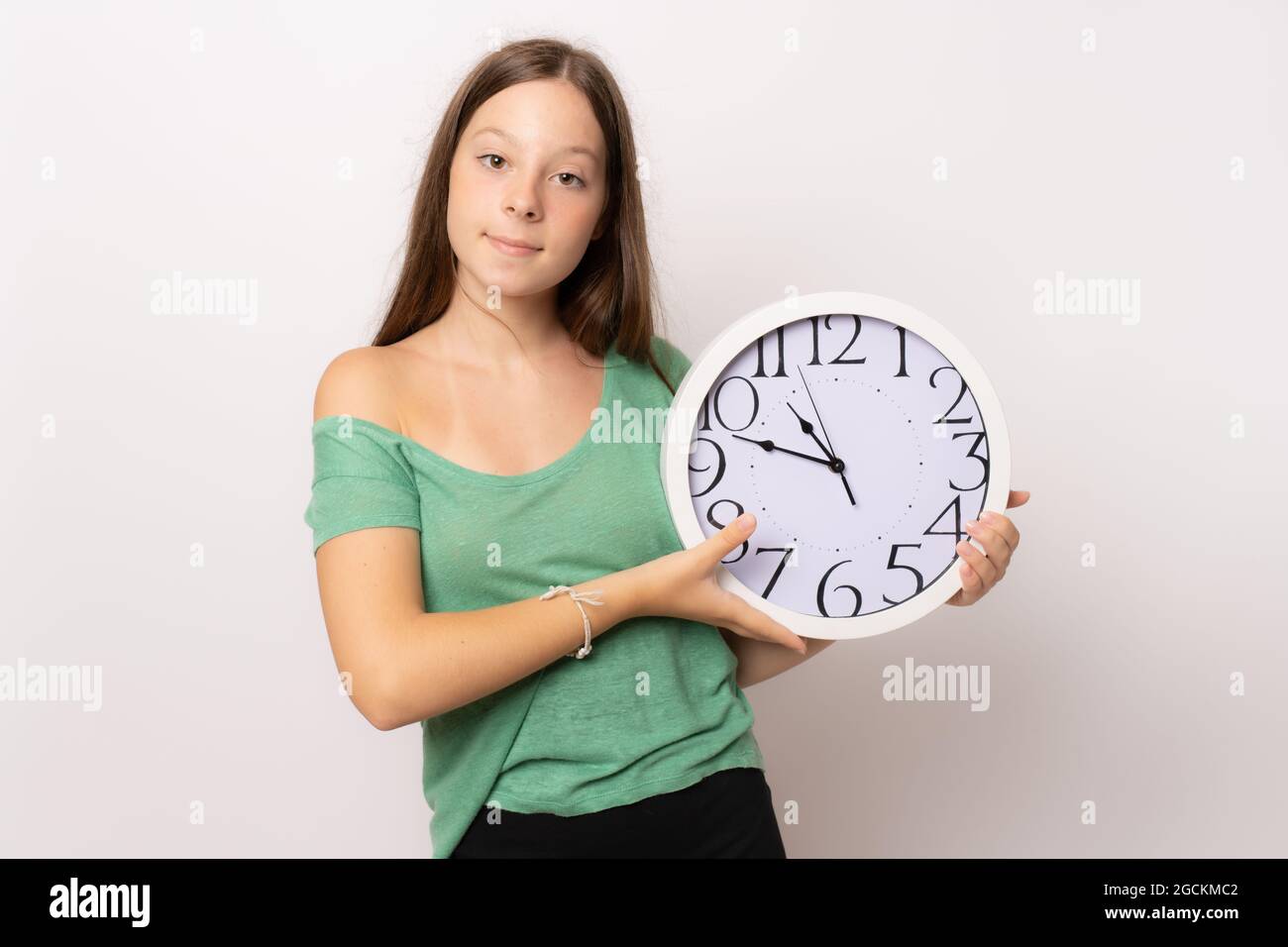 Young girl showing clock over white background Stock Photo - Alamy