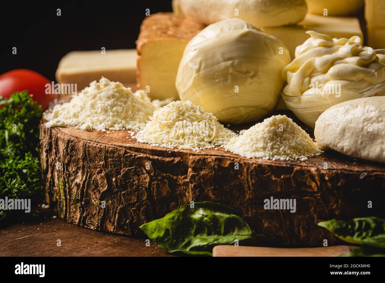 Collection of Italian cheese on table with fresh vegetables and curly ...