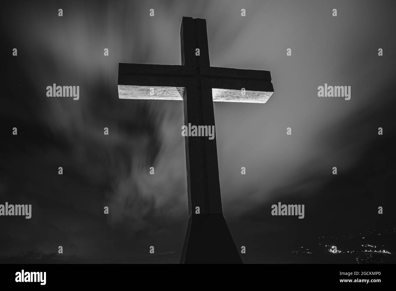 From below monument of a cross with background of clouds in the dark ...