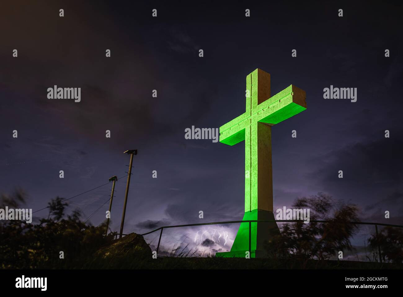 From below monument of a cross with background of clouds in the dark ...