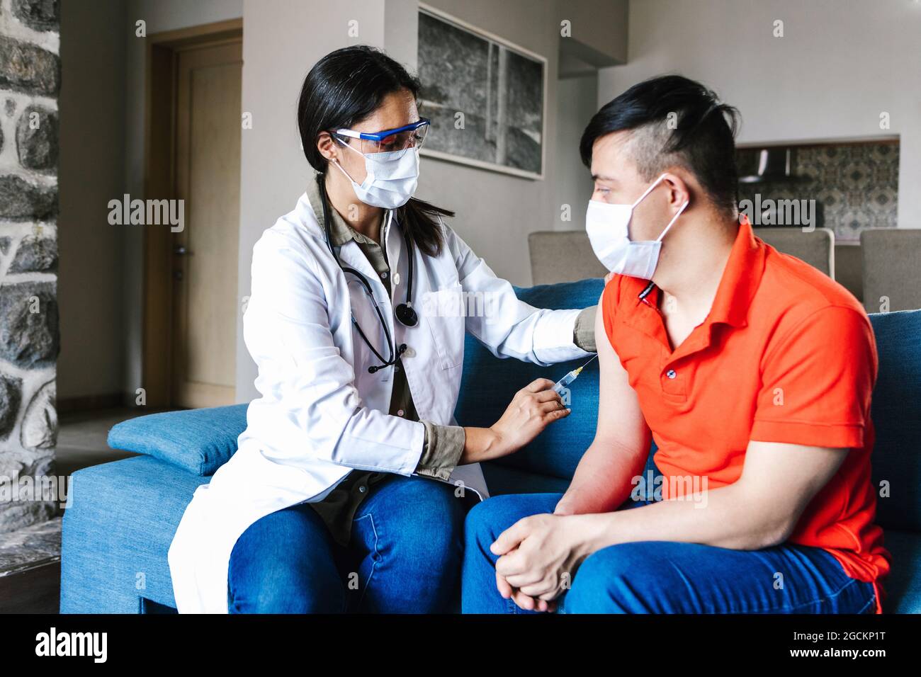Female medic with syringe making injection of vaccine for Latin teenage ...