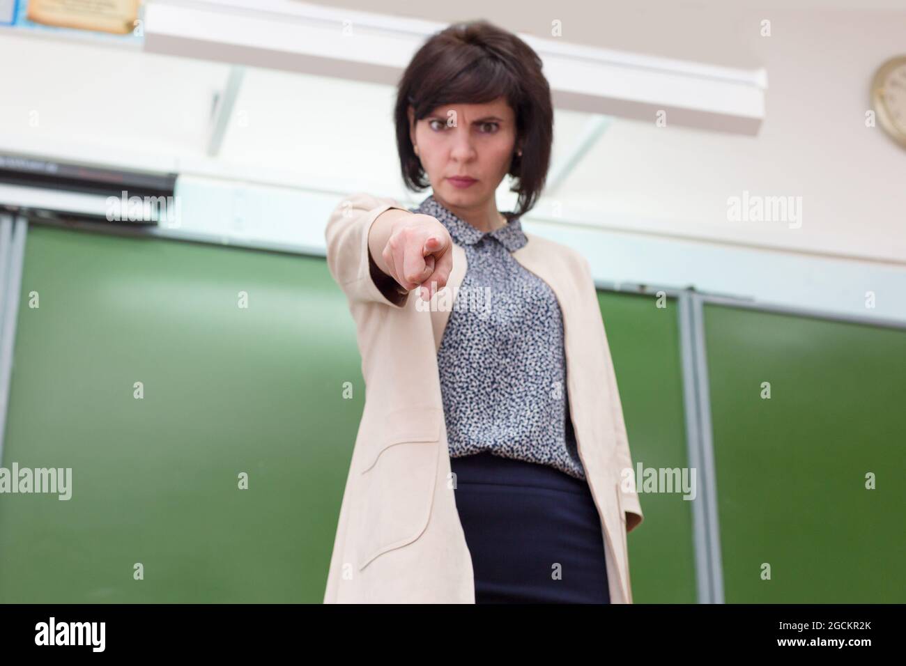 A very angry teacher demands an answer from a student with a hand ...