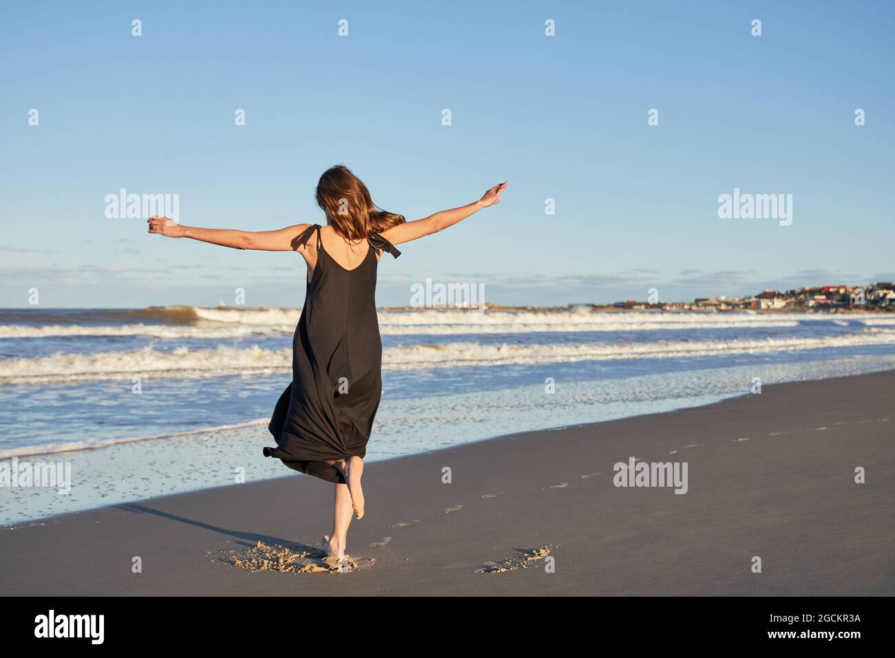 Full body back view of female in summer dress standing on sandy ...