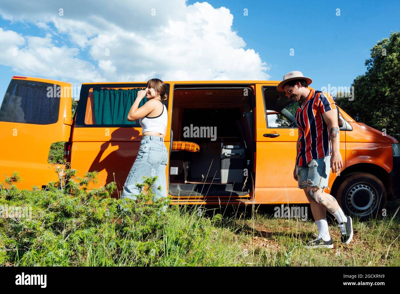 Delighted couple of travelers standing in van and during summer ...