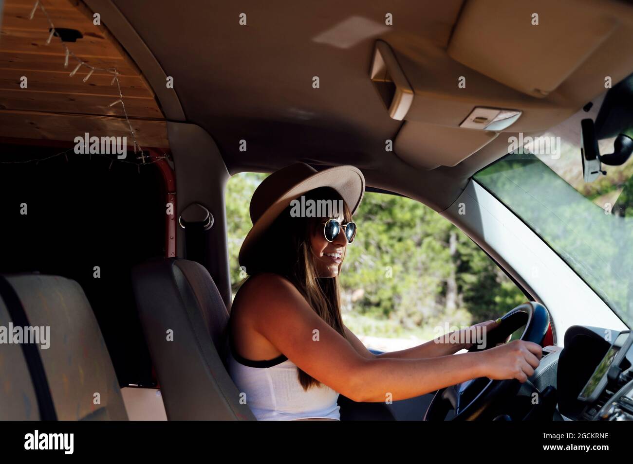Side view of female traveler sitting on driver seat in van and enjoying ...