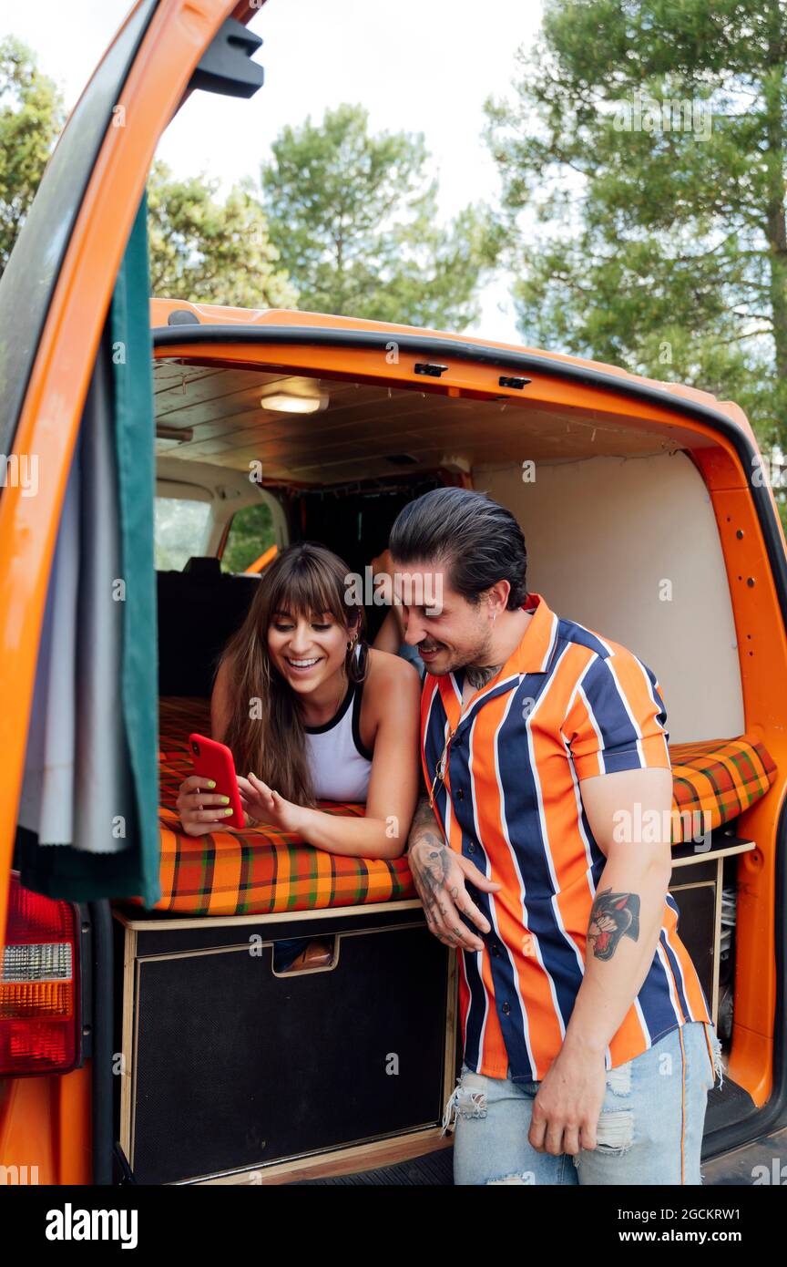 Delighted couple of travelers sitting in van and taking self shot on ...
