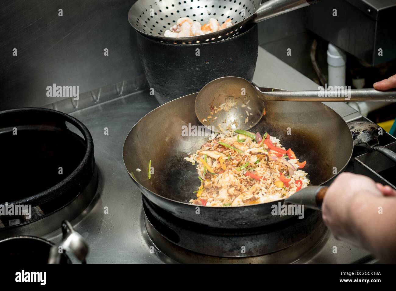 High angle of crop anonymous chef frying rice with vegetables in wok ...