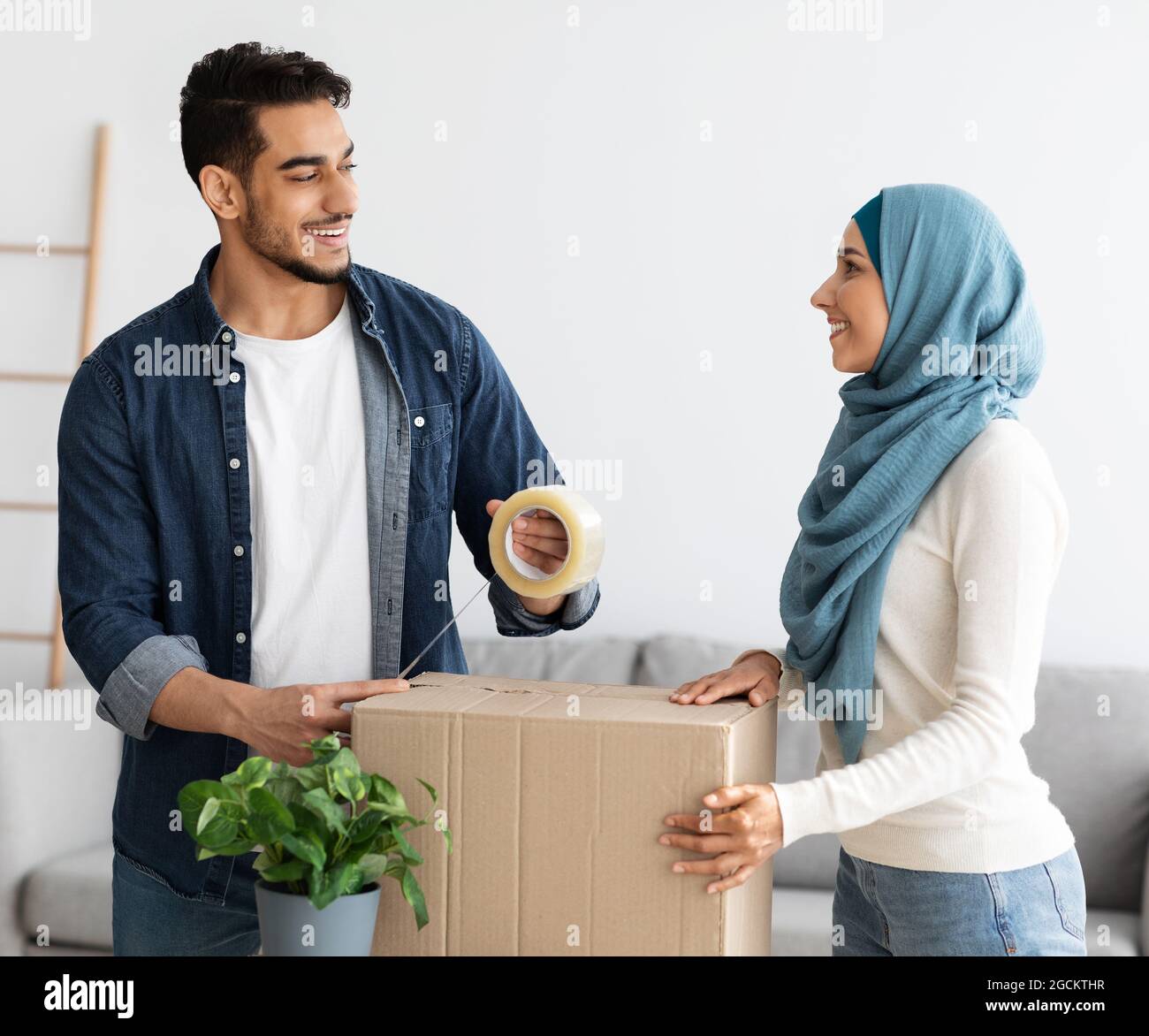 Beautiful young muslim couple moving to new house, packing belongings ...