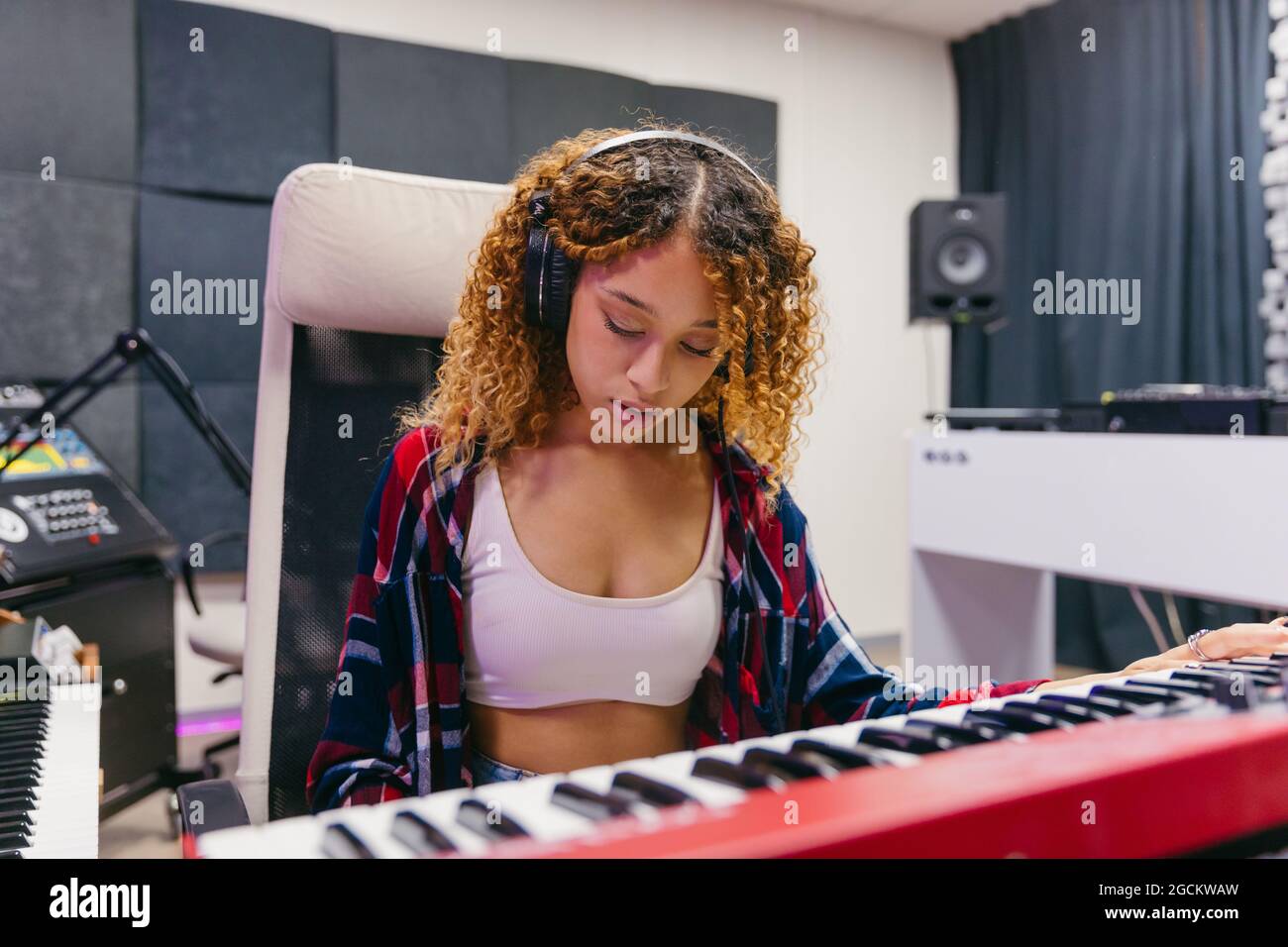 Focus African American female singer in headset playing synthesizer ...
