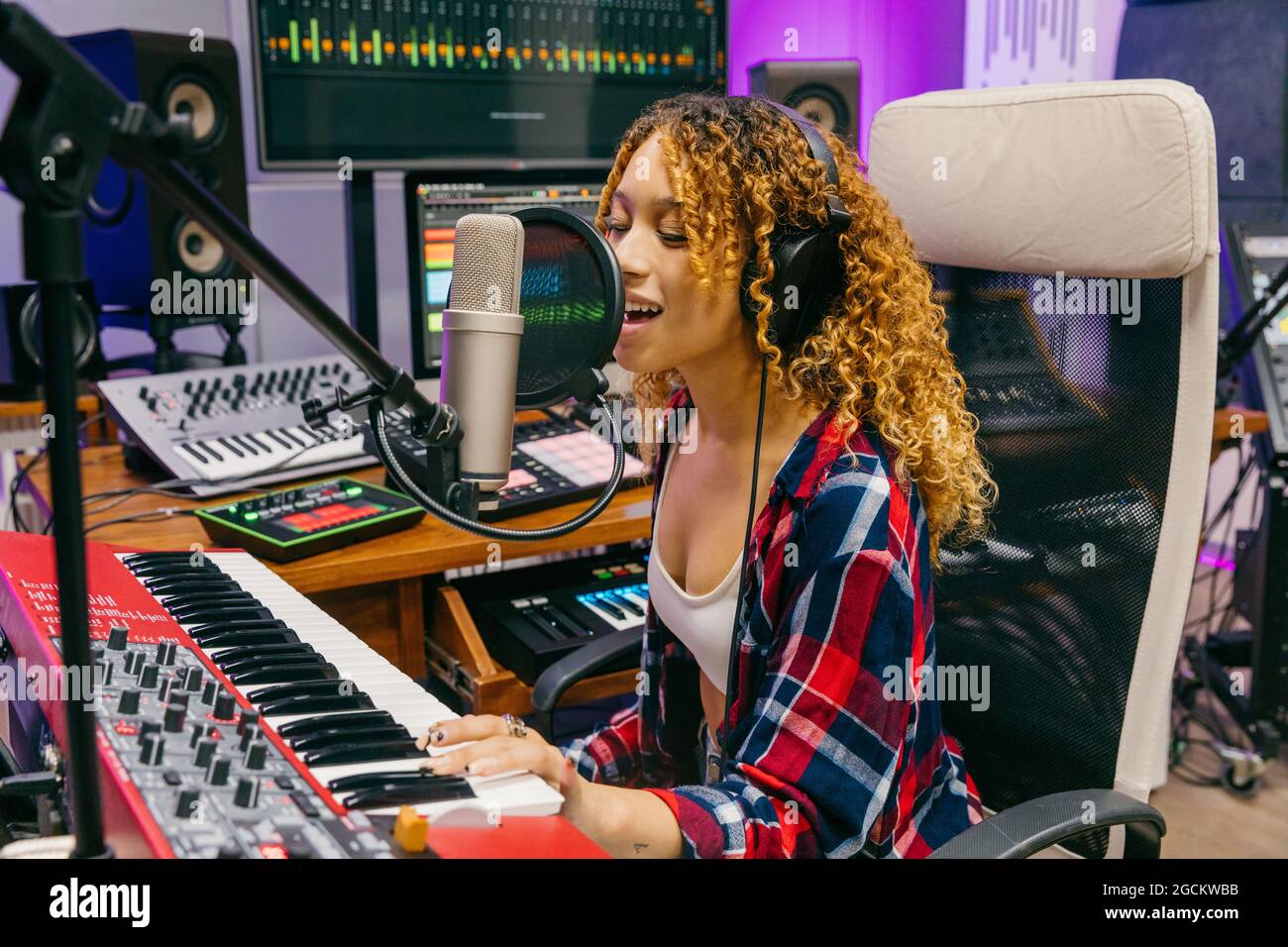 Side view of smiling African American female singer in headset playing ...