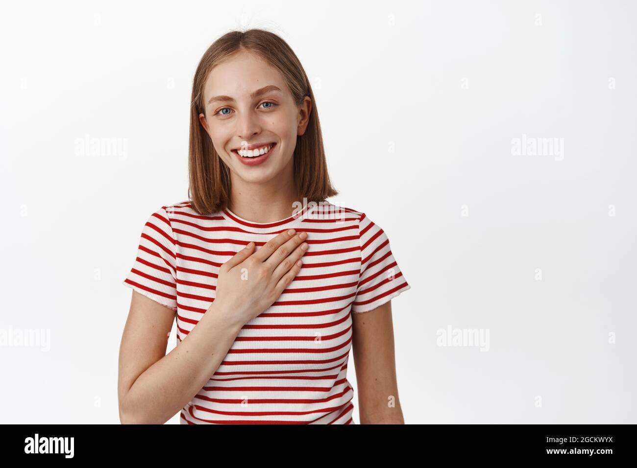 Thank you. Smiling young woman, student hold hand on chest and looking ...