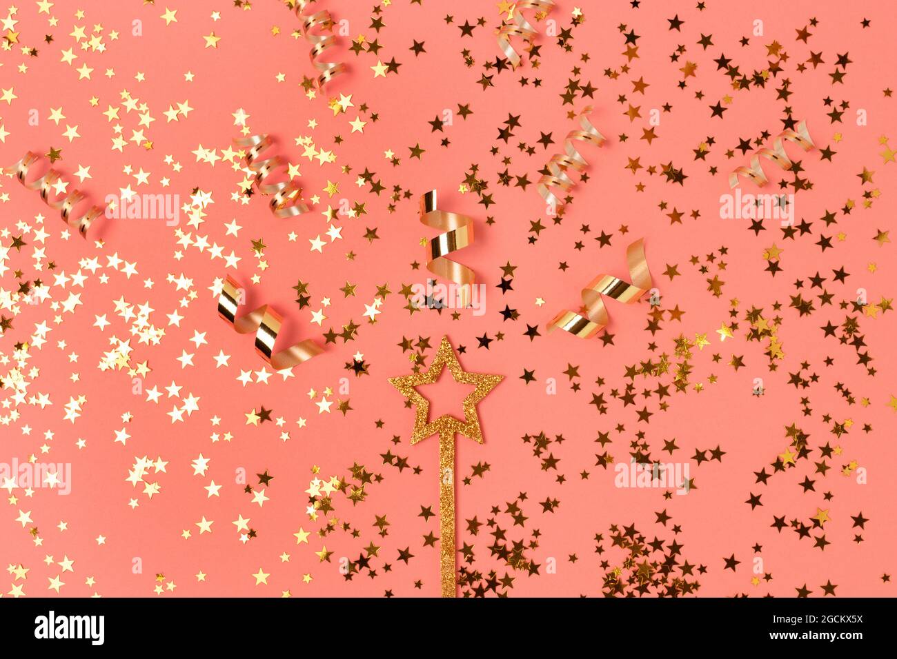 Glittering magic wand with gold colored confetti on a coral background ...