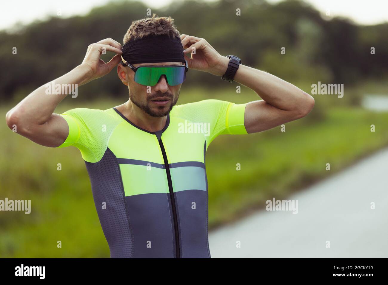 Young professional male triathlete, runner exercising outdoors on open ...