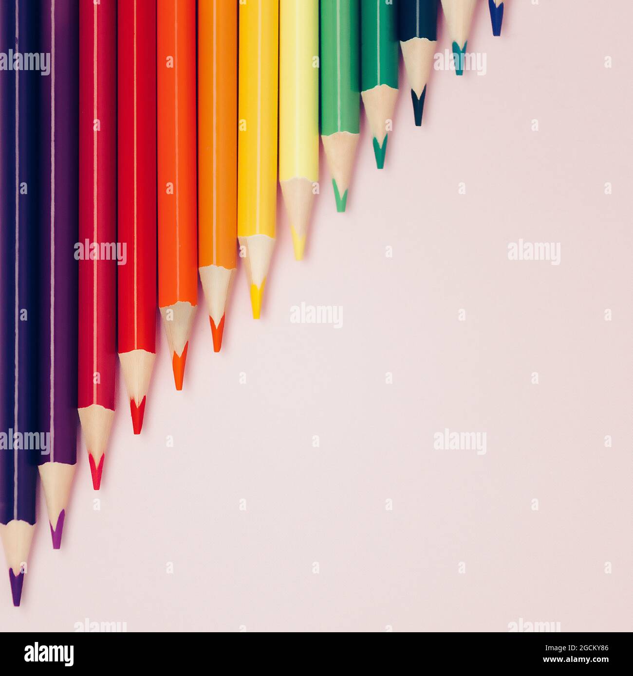 Colored pointed pencils lie on a pink background with space for copying ...