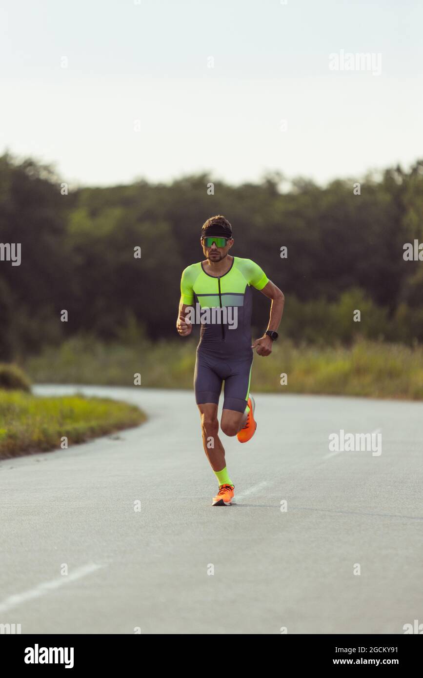 Young professional male triathlete, runner in motion on open road ...
