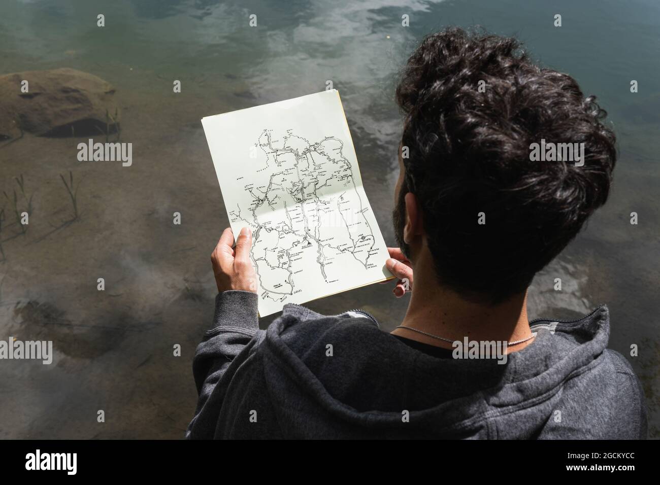 Back view of unrecognizable male explorer reading paper map and ...