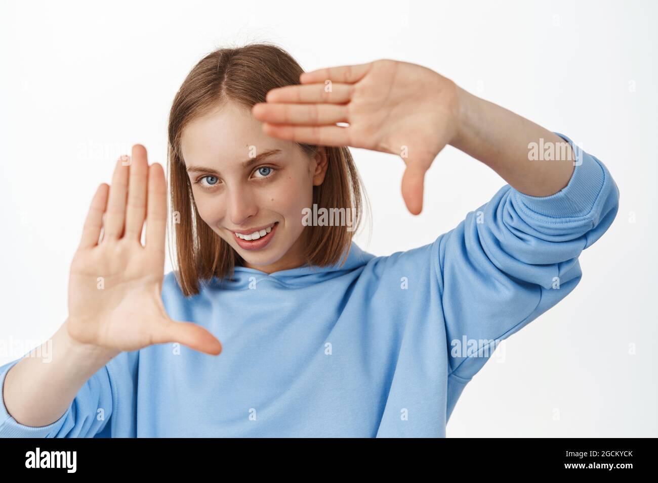 Image of creative young woman looking through hand frames gesture with ...