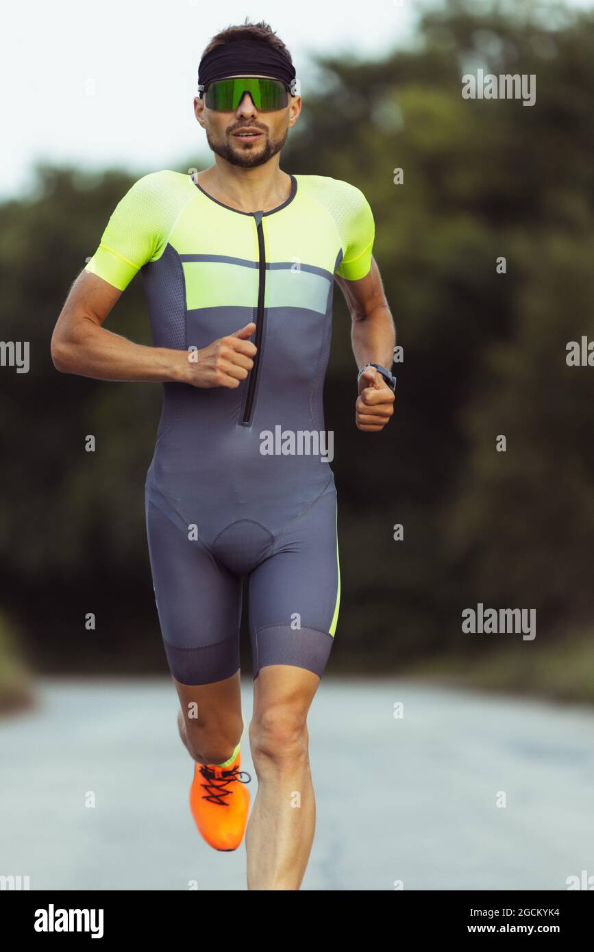 Young professional male triathlete, runner in motion on open road ...