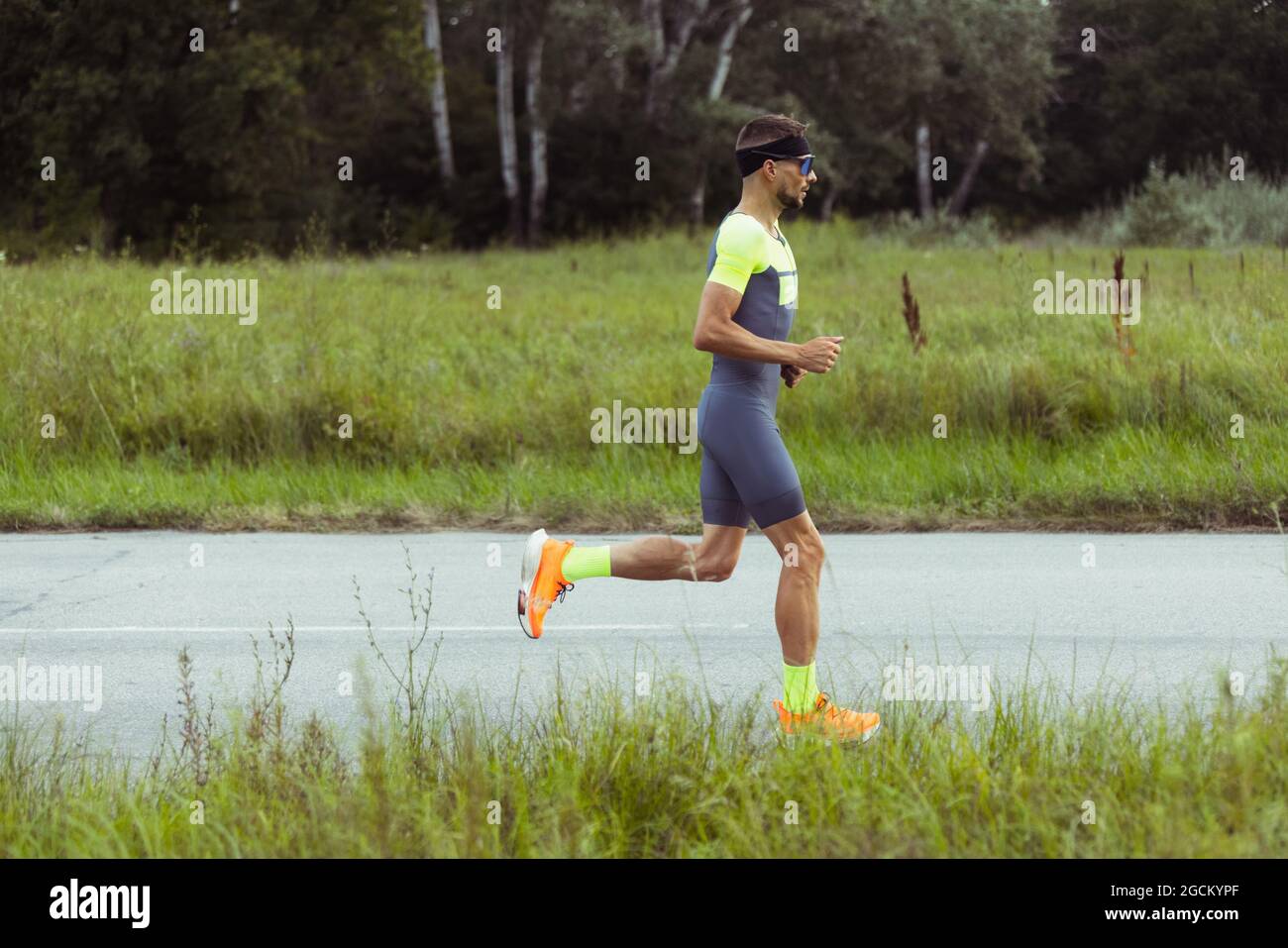 Young professional male triathlete, runner in motion on open road ...